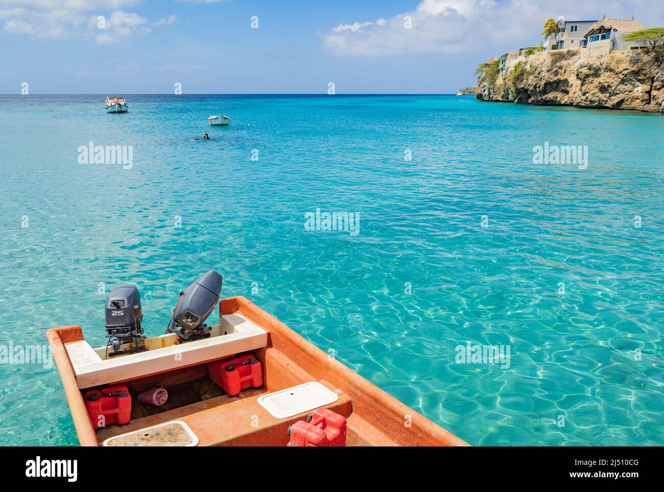 Small orange and white fishing boat on the crystal clear, turquoise ...