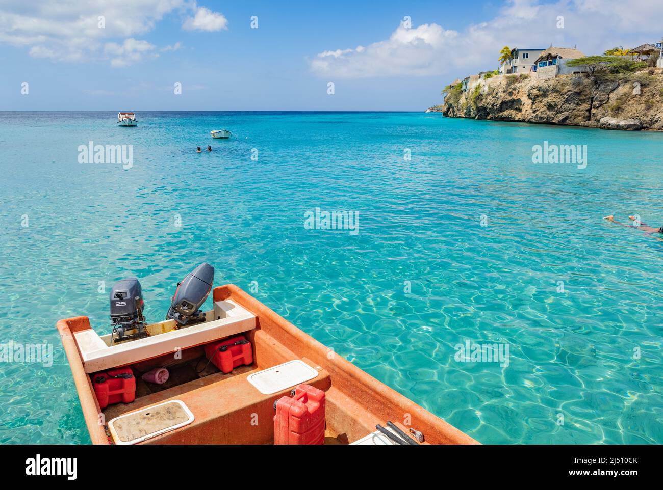 Small orange and white fishing boat on the crystal clear, turquoise ...
