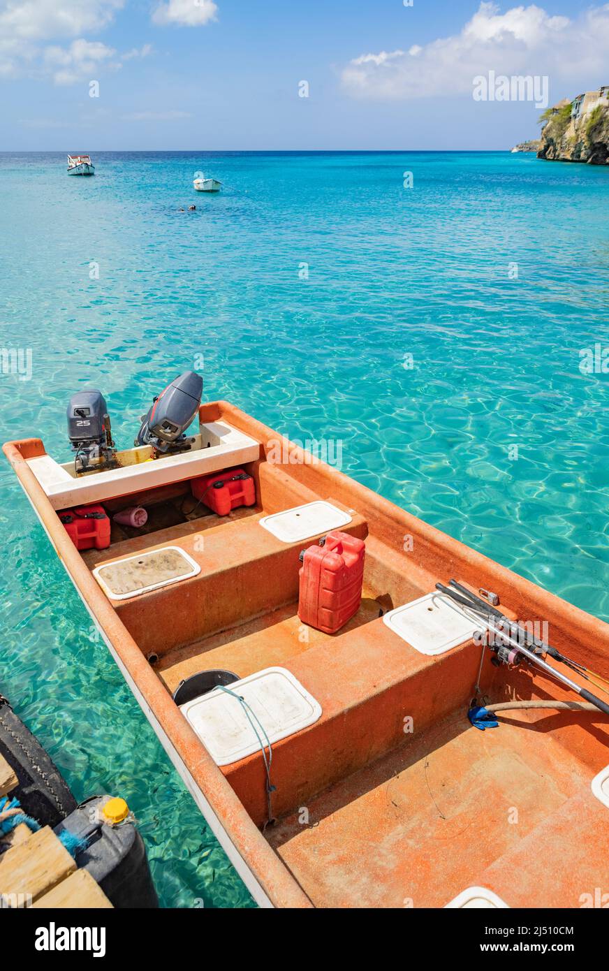 Small orange and white fishing boat on the crystal clear, turquoise ...