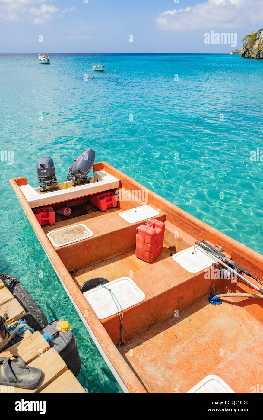 Small orange and white fishing boat on the crystal clear, turquoise ...