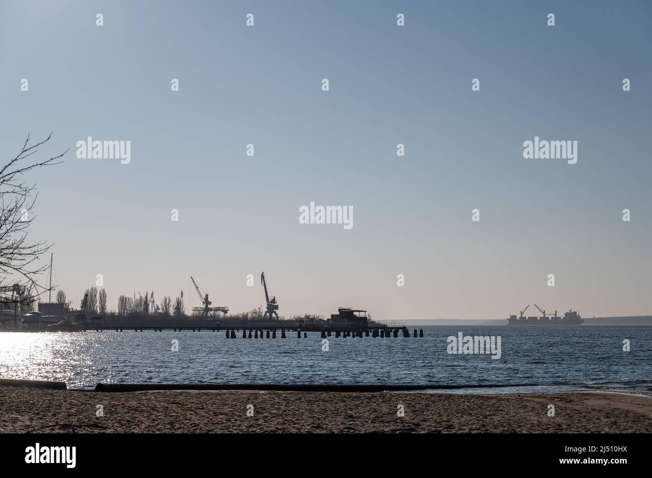 A dry cargo ship with open bilges is anchored in the middle of a wide ...