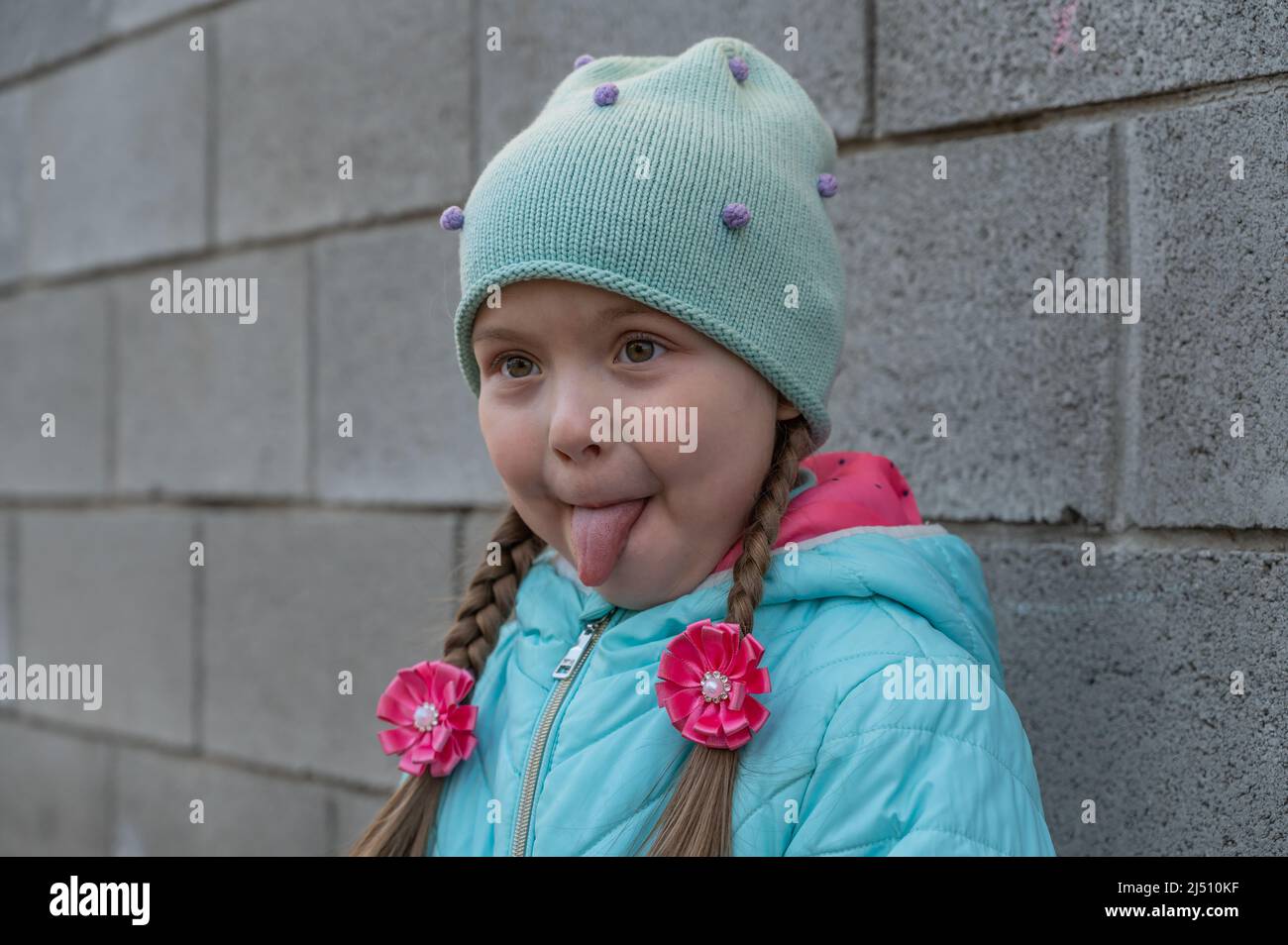 A portrait of a child against a gray stone wall. A five-year-old girl ...