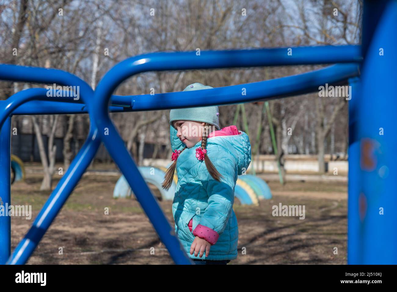 A girl with a long pigtail stands on the playground. A five-year-old ...