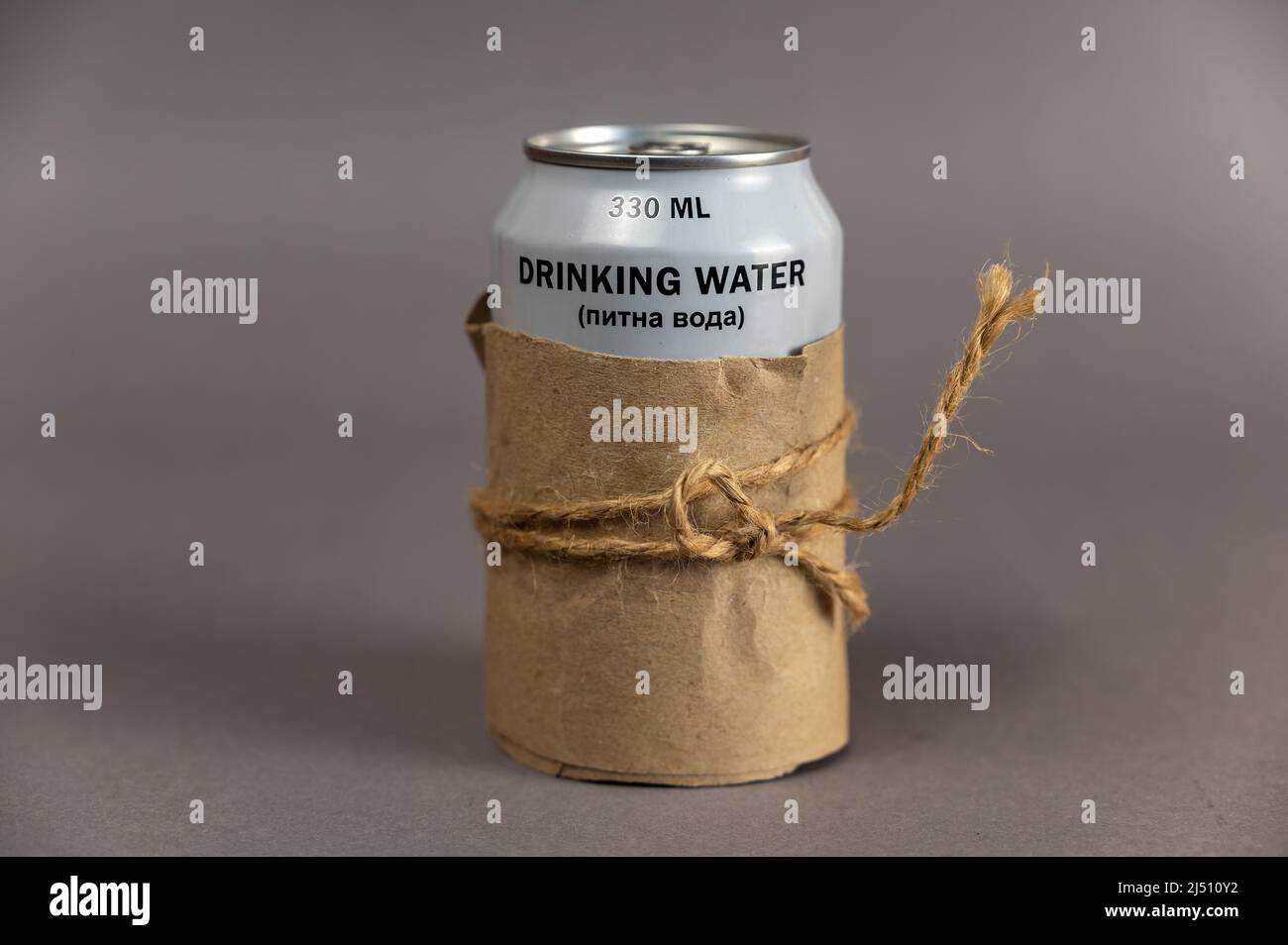 Cylindrical can of drinking water in front of the gray background ...