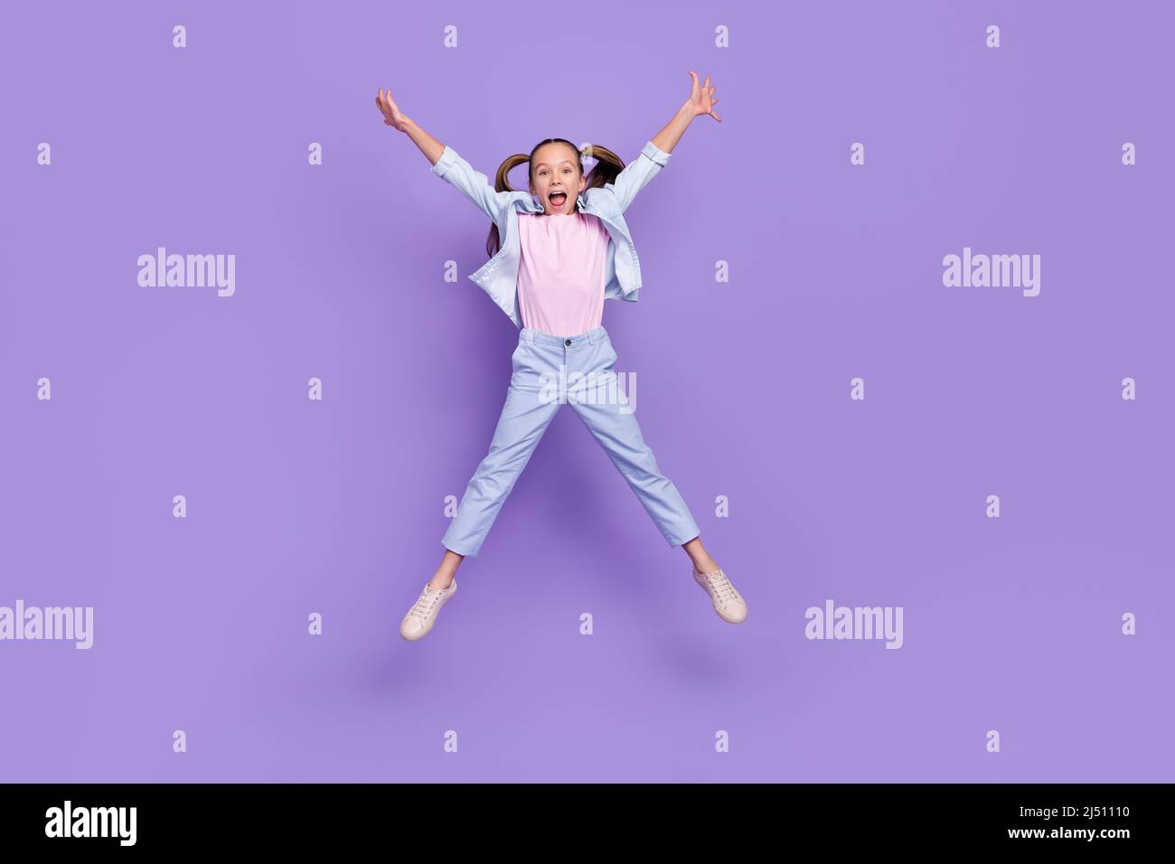 Photo of excited pretty little school girl wear denim shirt jumping ...