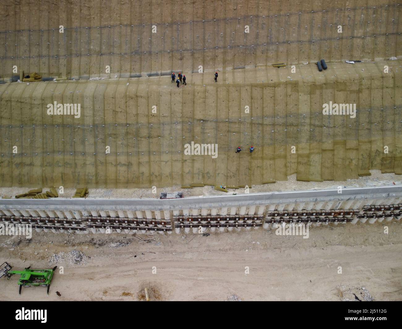 Workers reinforce the slope over the new road. Road construction in ...
