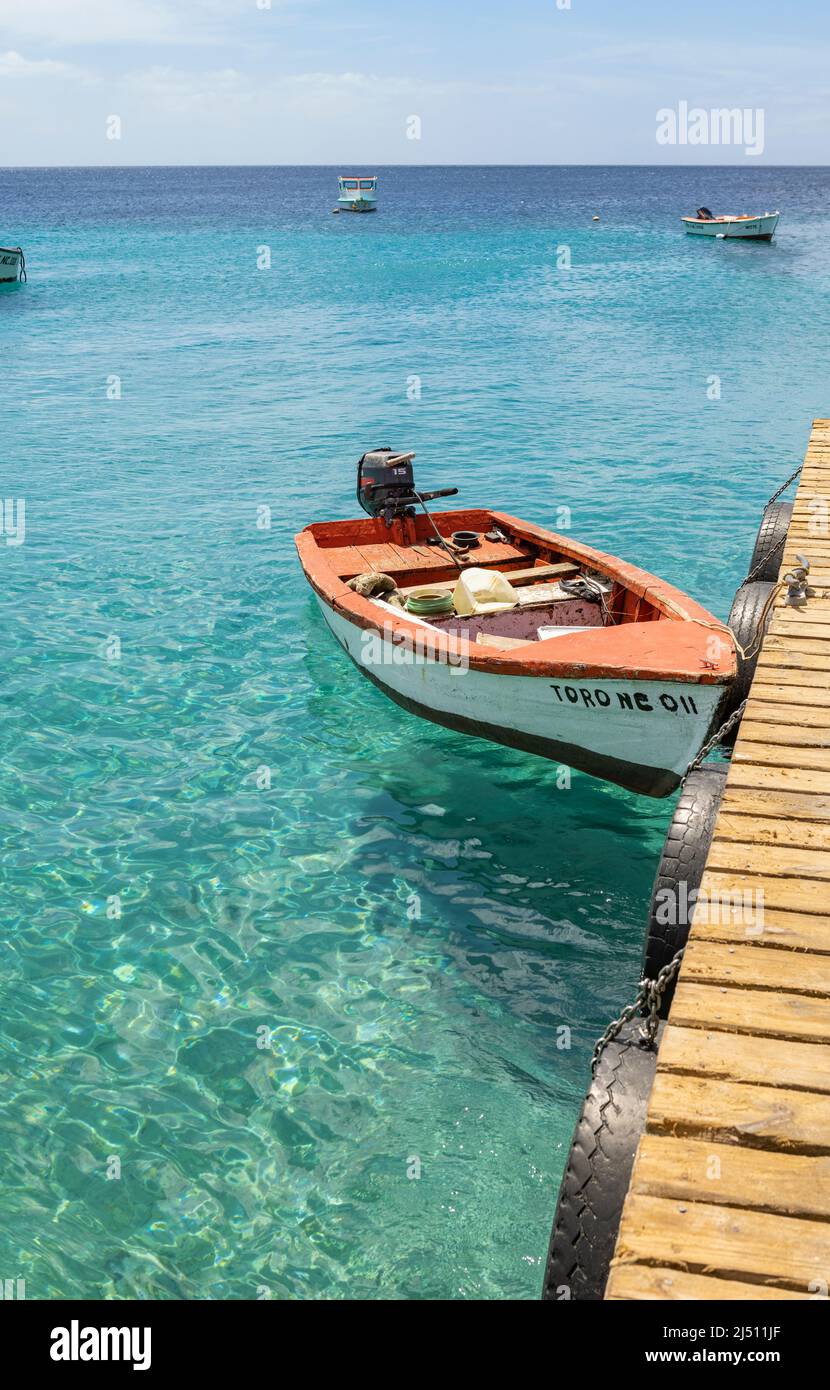 Small orange and white fishing boat on the crystal clear, turquoise ...