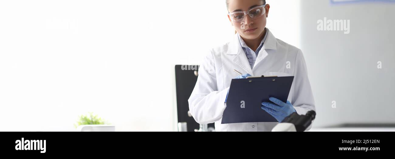 Woman scientist chemist writing in documents in chemical laboratory ...