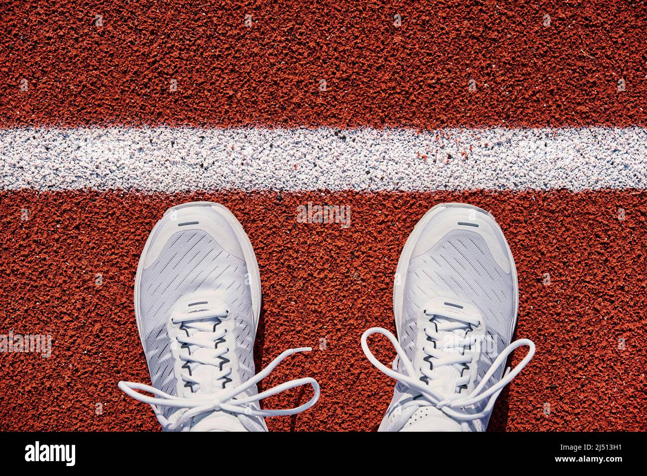 Top view of white male running sneakers near start line at stadium ...