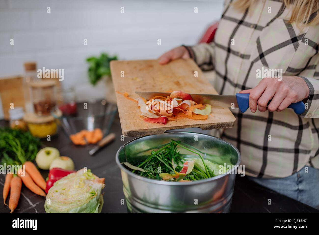 Woman throwing vegetable cuttings in a compost bucket in kitchen Stock ...