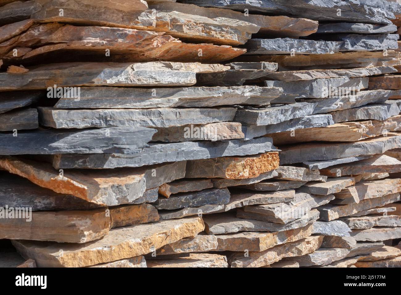 Slabs of natural stone stacked in layers. Folded flagstone. Horizontal ...
