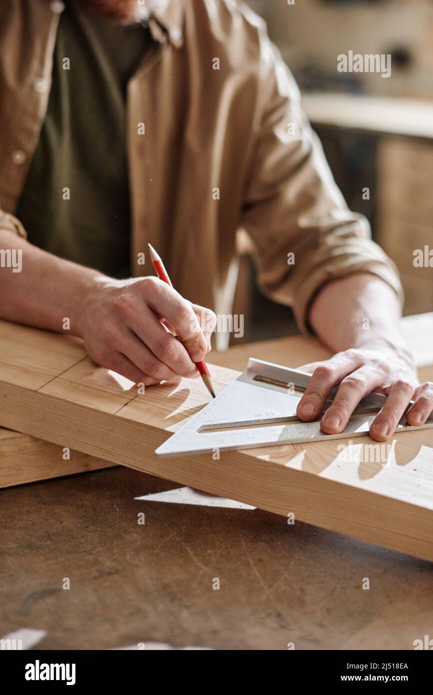 Vertical shot of unrecognizable carpenter drawing marks using ruler and ...