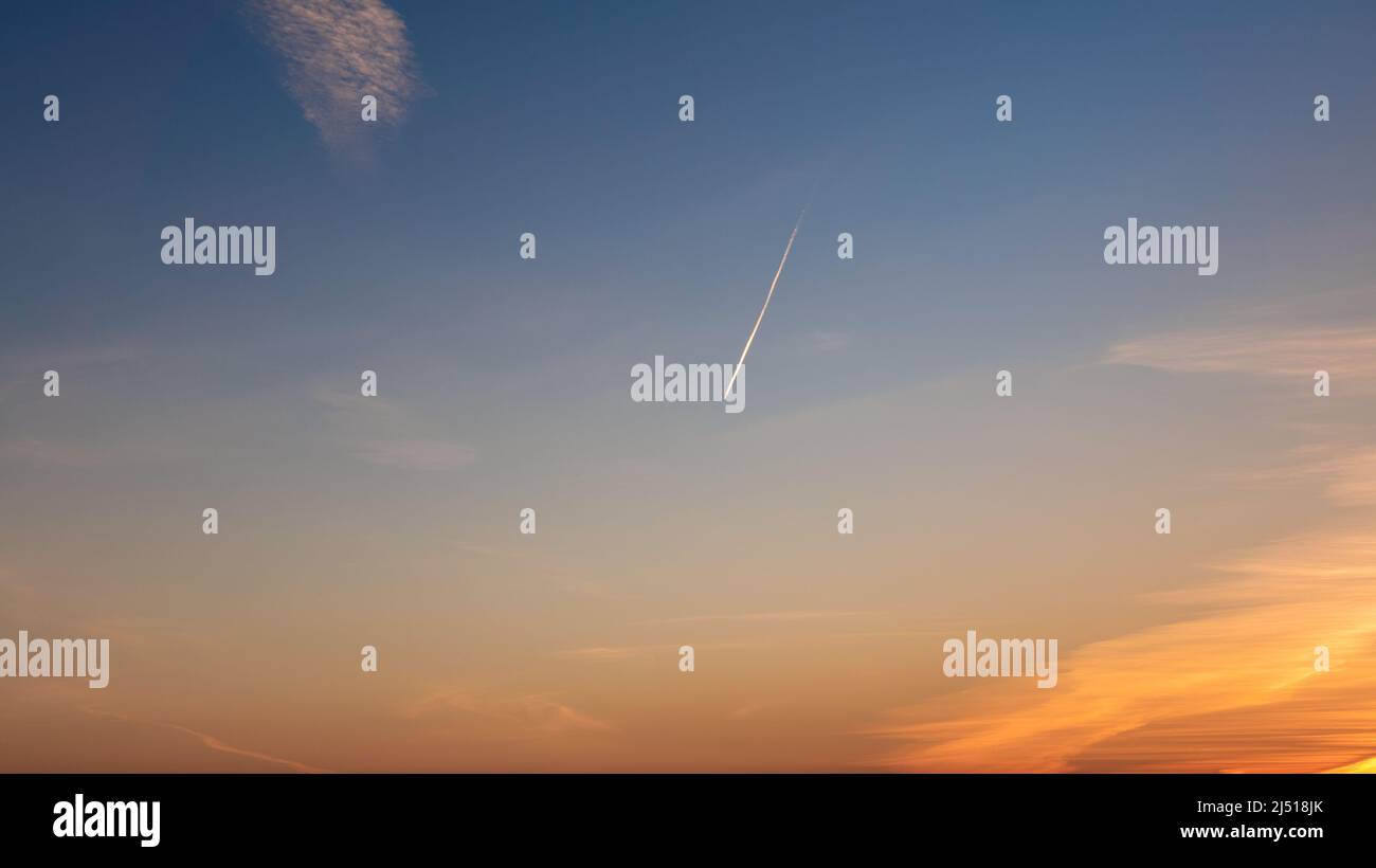 Passenger plane flying in the blue sky at sunset, fast transport leaves ...