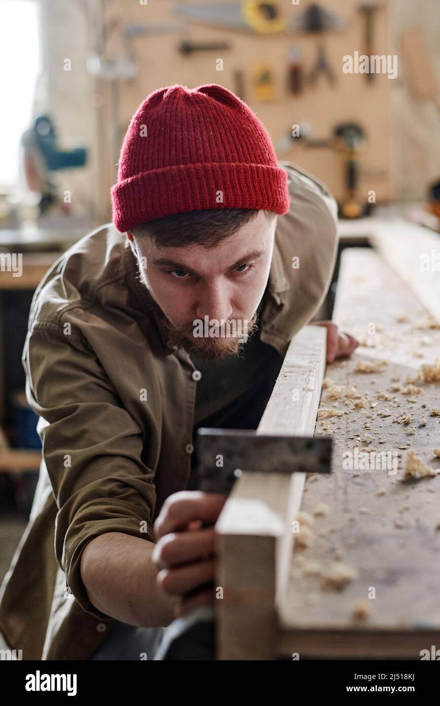 Vertical shot of serious young male carpenter using steel square when ...