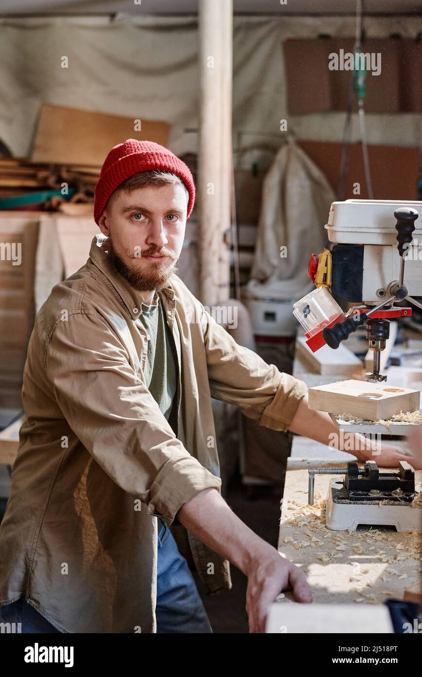 Vertical medium portrait of young Caucasian male carpenter wearing red ...