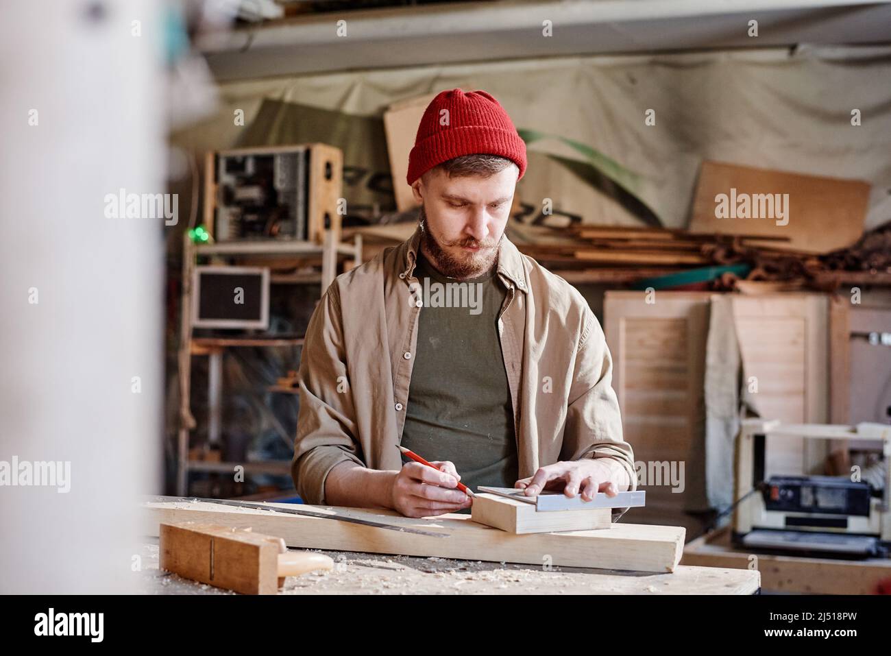 Professional young male carpenter using ruler and pencil making marks ...