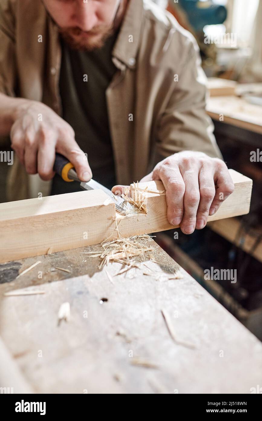 High angle medium close-up of man working in carpentry workshop cutting ...