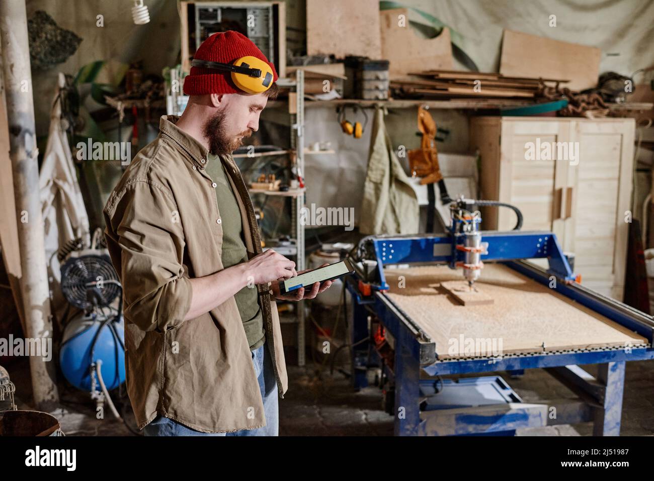 Modern professional carpenter standing in woodworking workshop using ...
