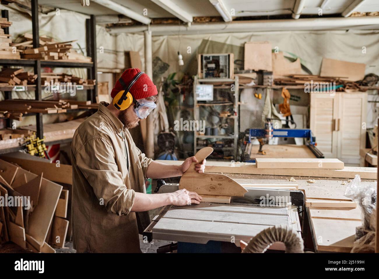Young male carpenter wearing safety glasses and hearing protection ...