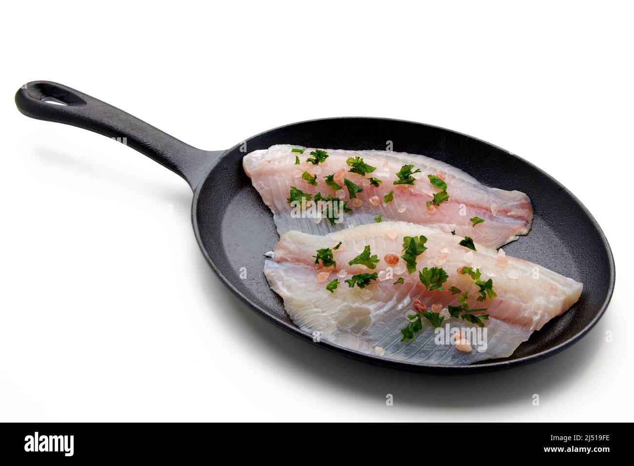 Two fillets of white fish, spilled with salt and chopped parsley in a ...
