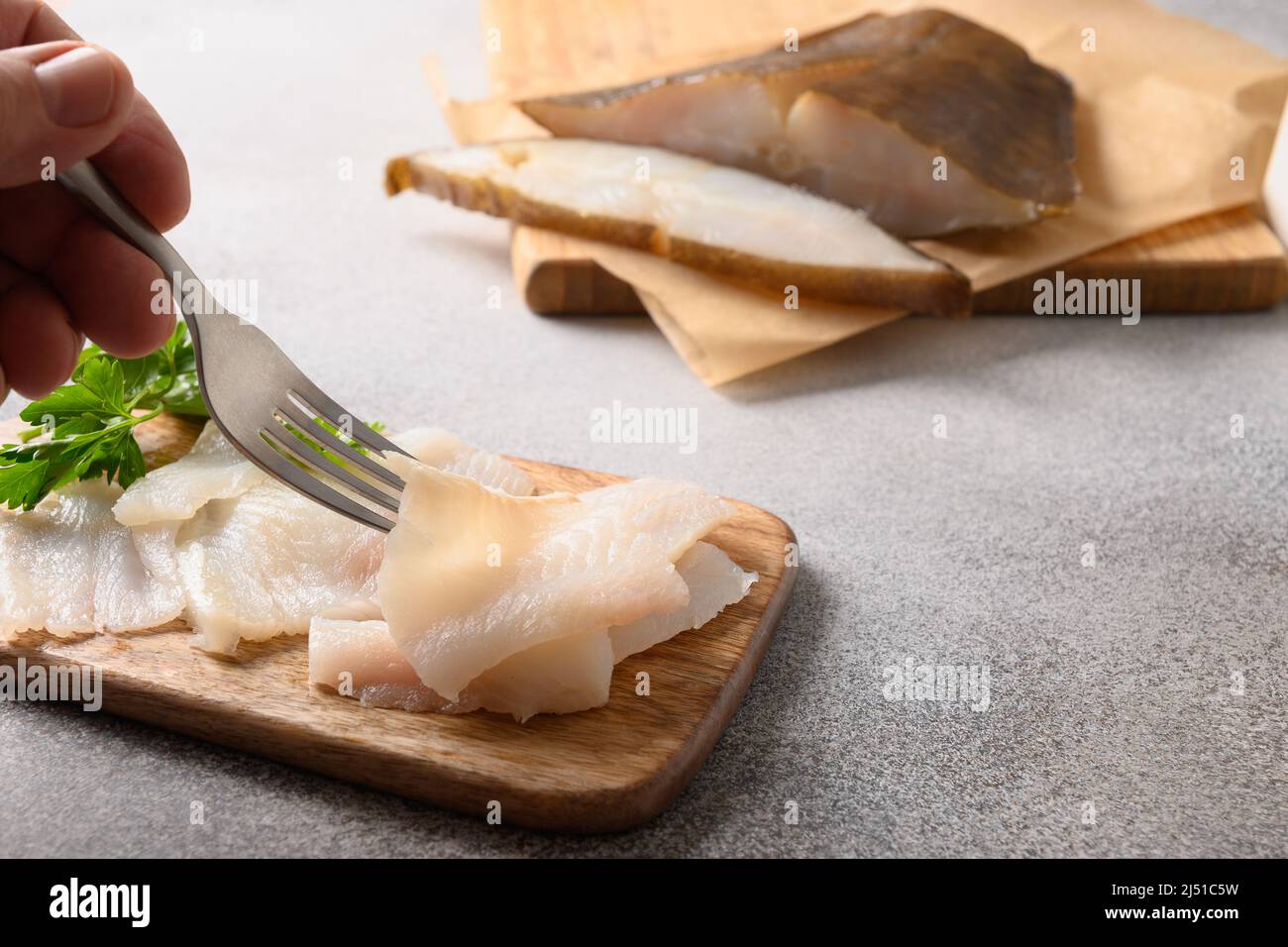 Smoked halibut slices on gray background. Man eating delicacy fish ...