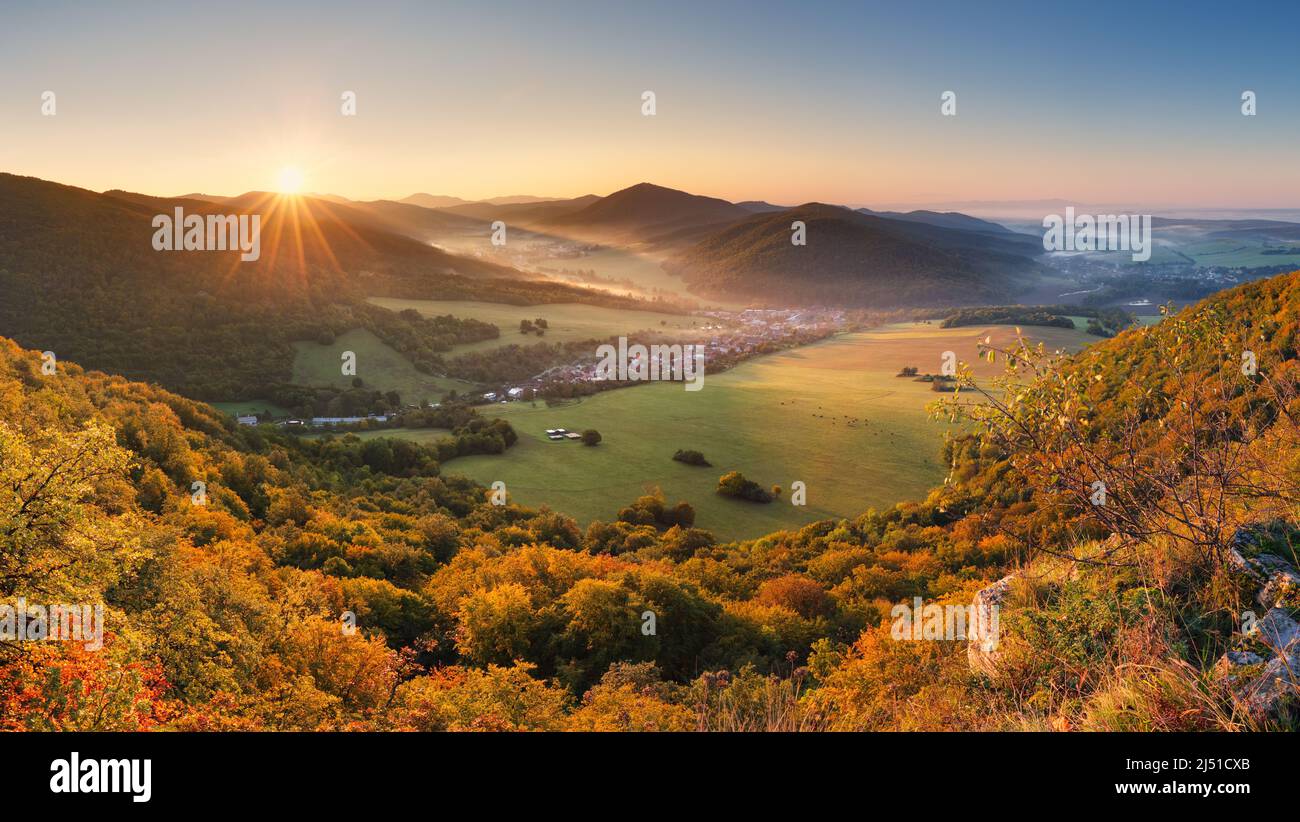 Countryside rural landscape with village over sunbeam in misty morning ...