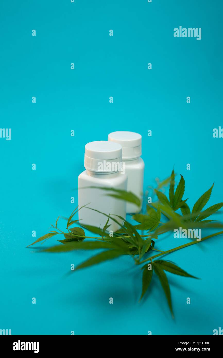 two white jars and cannabis leaves on a blue background Stock Photo - Alamy