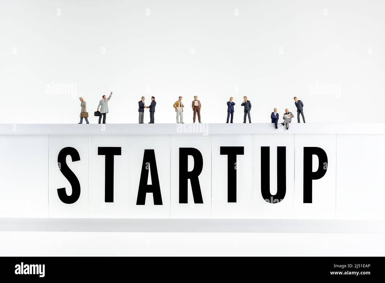 Startup concept. Miniature people on top of the lightbox with a word ...