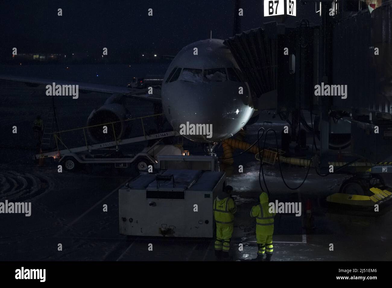 Airport workers prepare a plane for takeoff during a snowstorm in ...