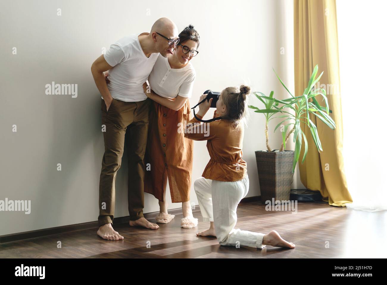 Little daughter taking picture of her parents. Which are posing the ...