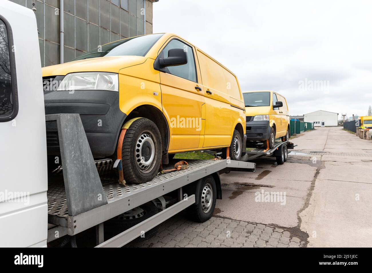 White small cargo truck car carrier loaded with two yellow van minibus ...