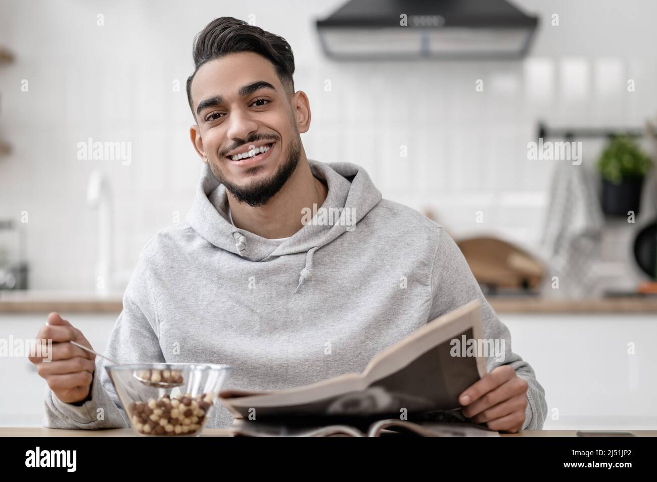 A young man having breakfast and reading a newspaper Stock Photo - Alamy