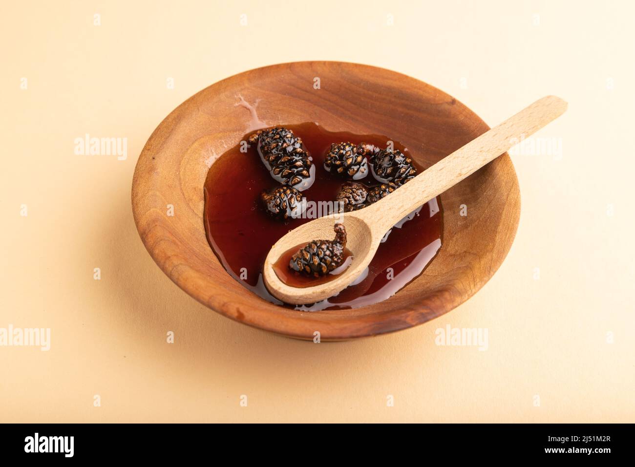 Pine cone jam in wooden bowl on orange pastel background. Side view ...