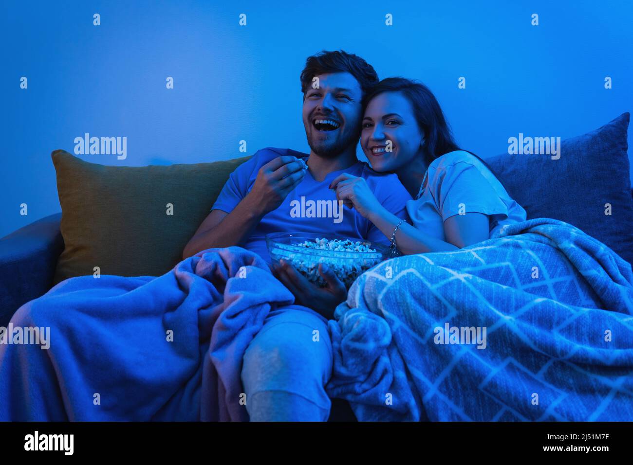 Young and happy couple watching comedy TV show at home Stock Photo - Alamy