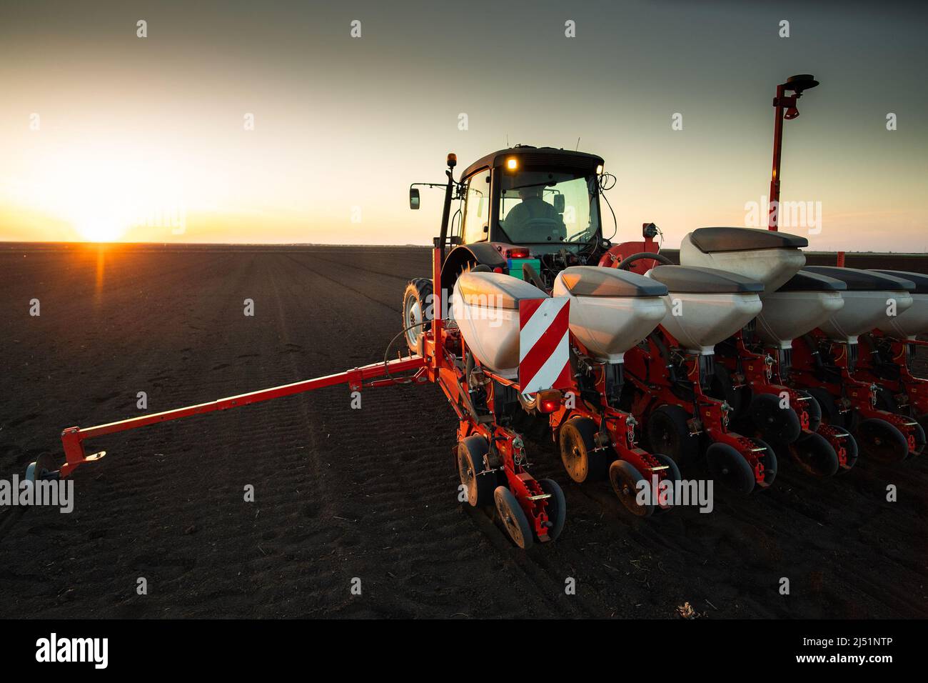 Farmer with tractor seeding - sowing crops at agricultural field ...