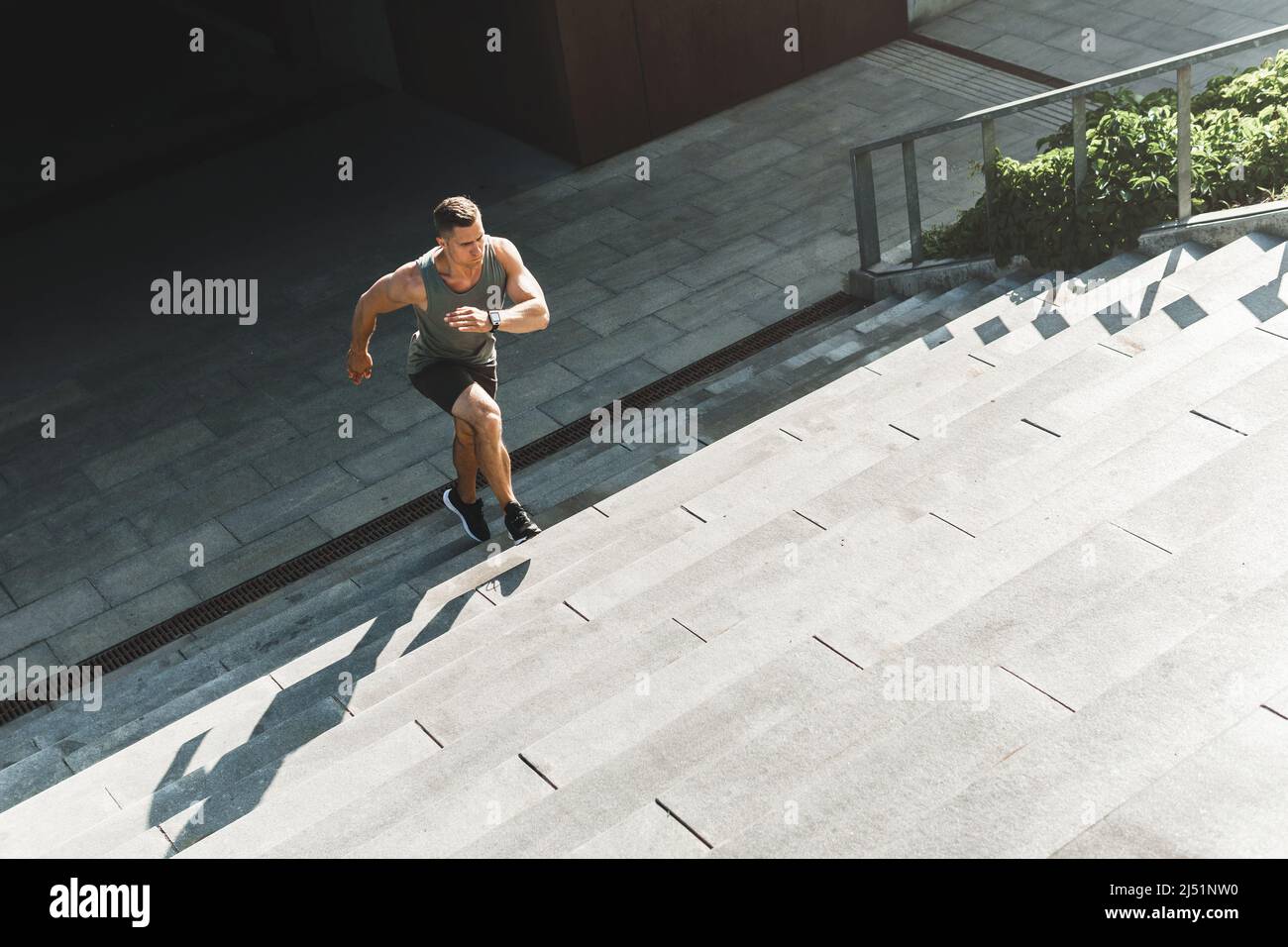 Muscular man is running upstairs by concrete staircase on the street ...