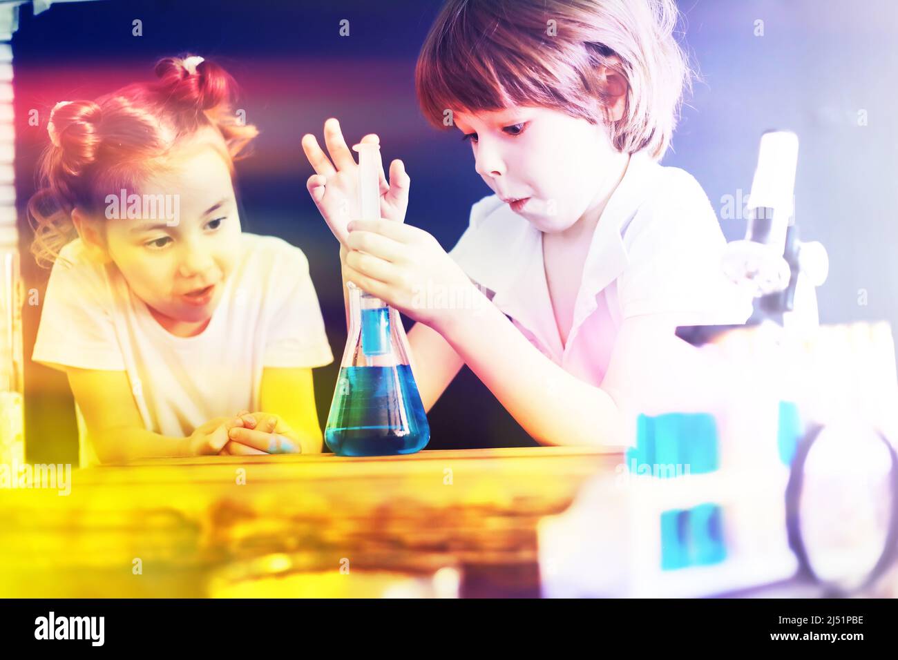 Children scientists. Schoolchildren in laboratory conduct experiments. Boy and girl experiments ...