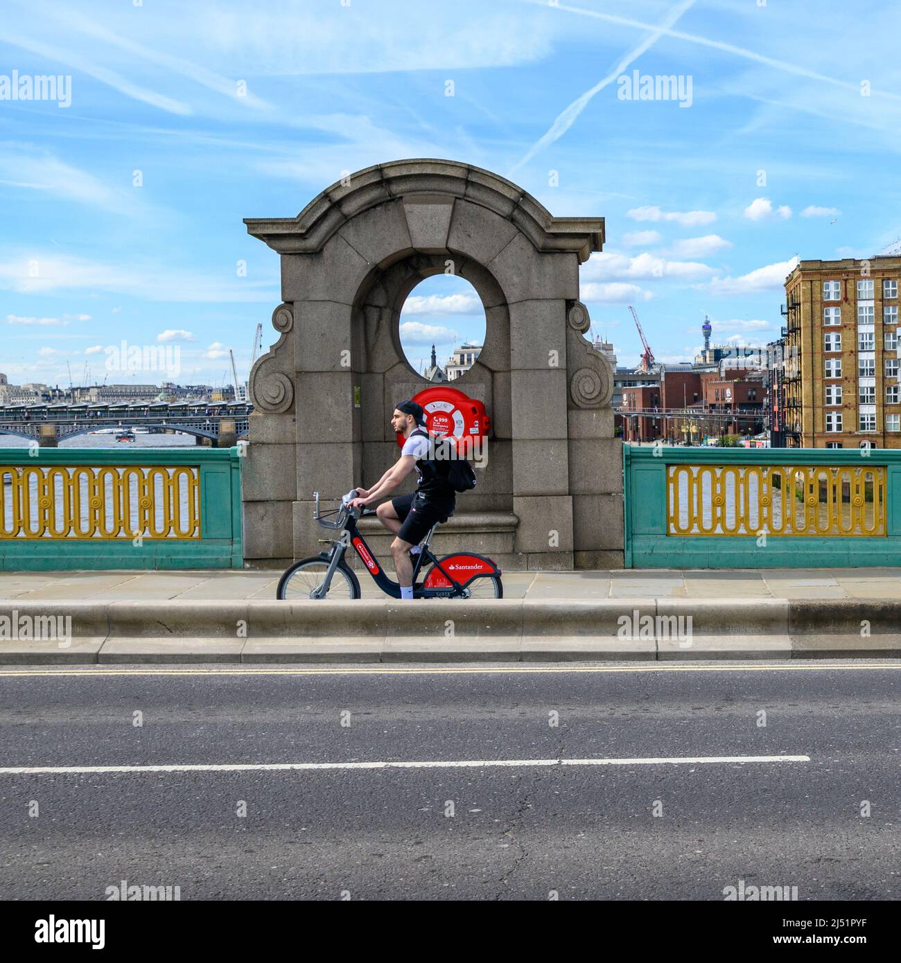 Man on a Santander hire bike cycling across Southwalk Bridge, London ...