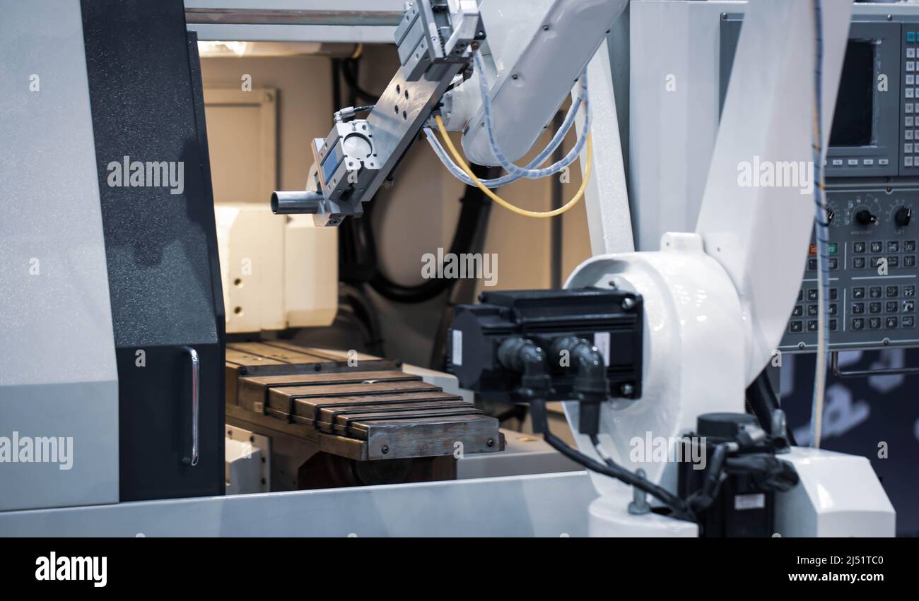 Modern factory. Robot feed workpiece on CNC lathe machine. Industrial ...