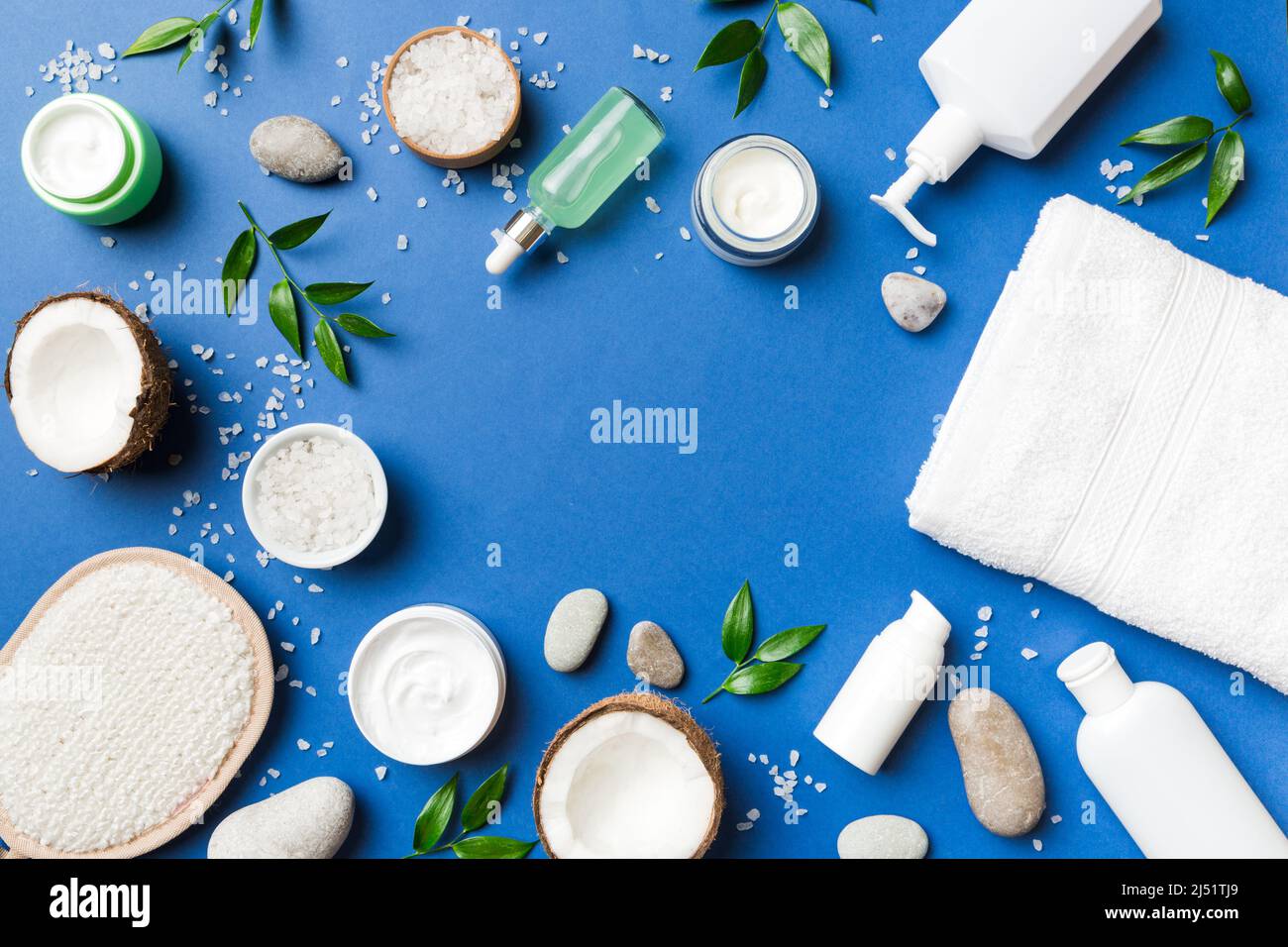 Coconut with jars of coconut oil and cosmetic cream on colored ...