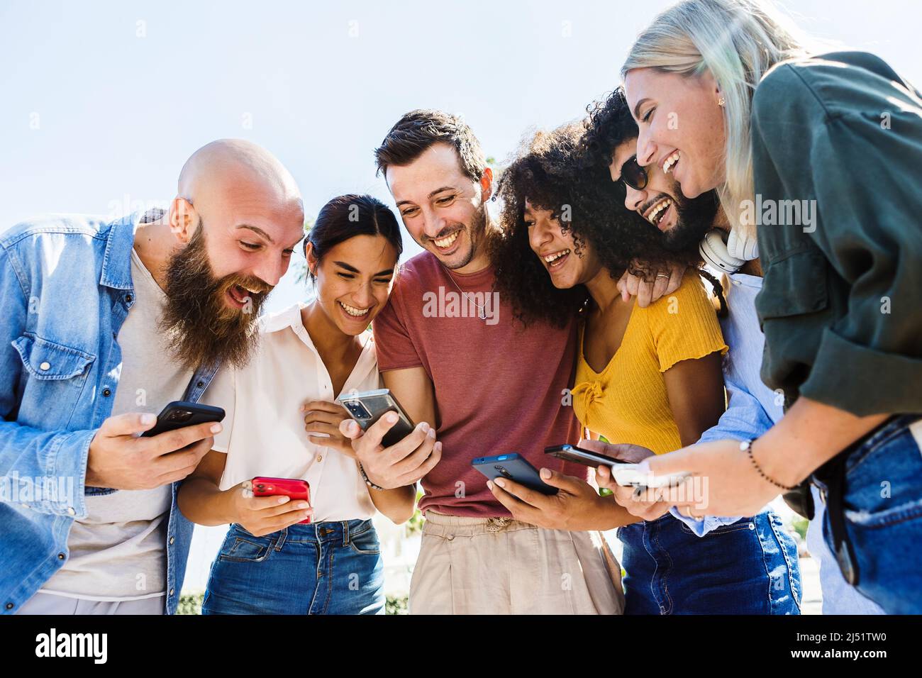 Young Group Of Happy People Smiling While Using Mobile Phone Together