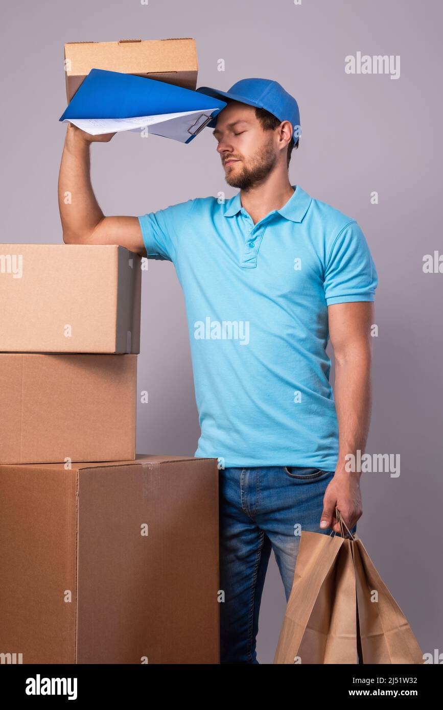 Tired delivery man during work with a packages in a cardboard boxes ...
