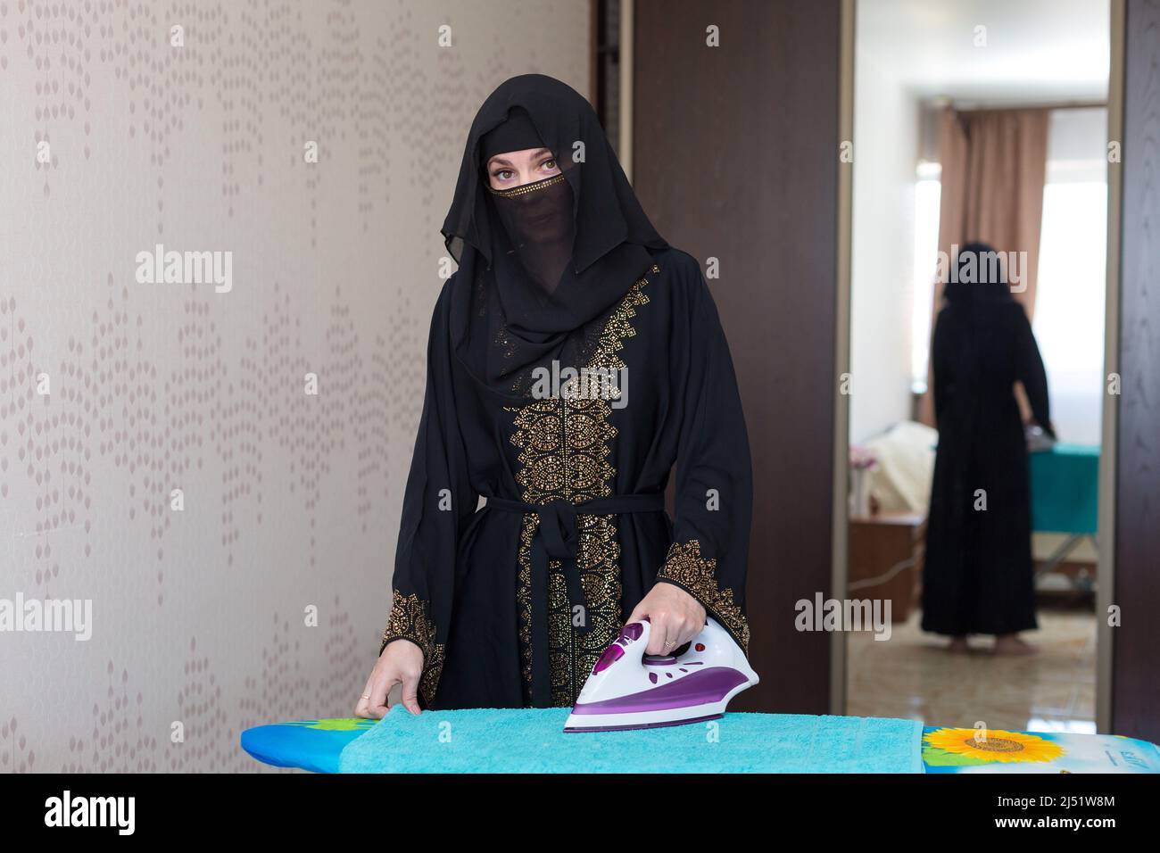 Muslim woman doing household chores ironing things Stock Photo - Alamy