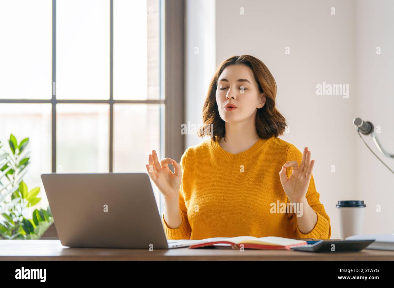 Woman working in the office and practicing deep breathing for calm and ...