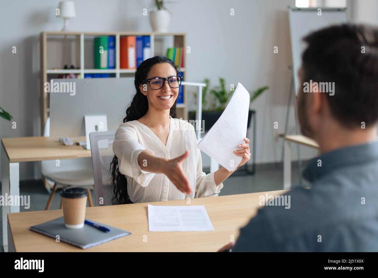 Happy HR manager holding CV, offering handshake to job applicant during ...