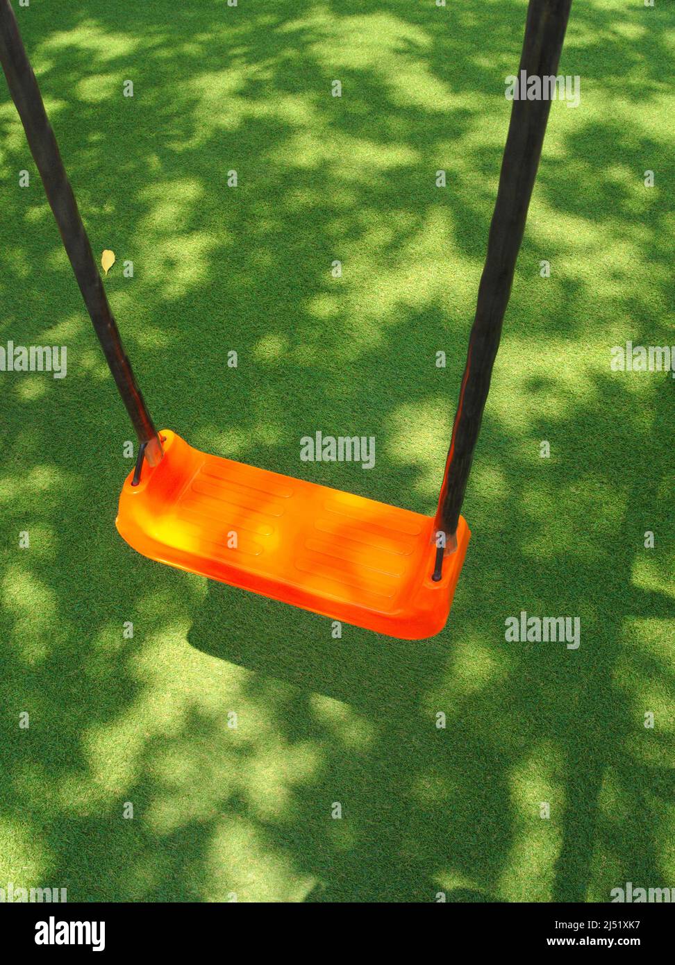 The vivid orange color Swing seat on the artificial grass school yard ...