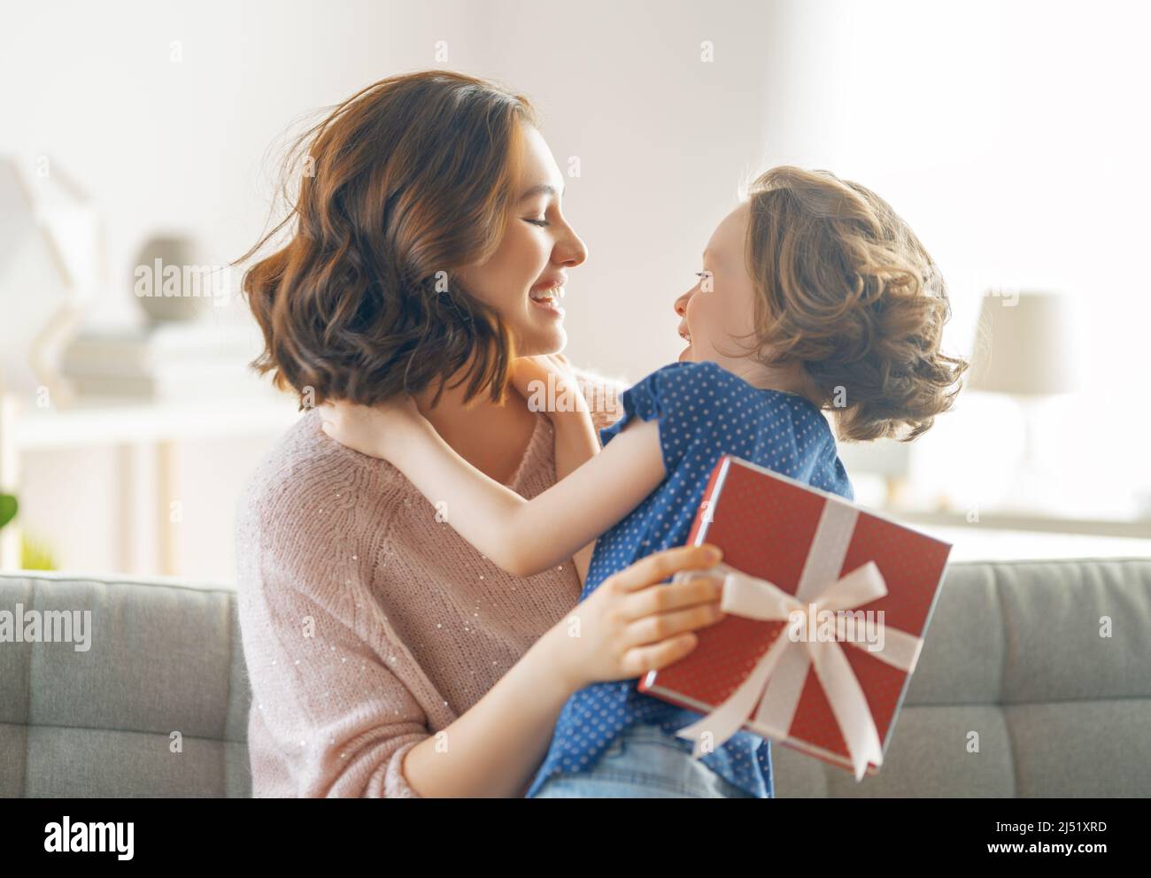 Happy mother's day. Child daughter is congratulating mom and giving her ...