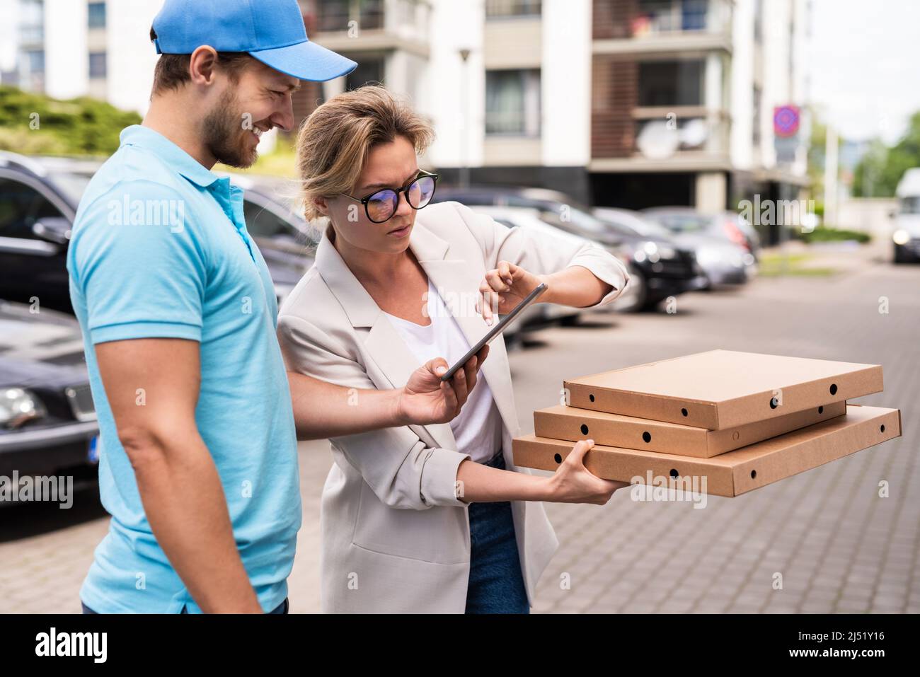 Professional delivery man wearing blue uniform delivers pizza to a ...