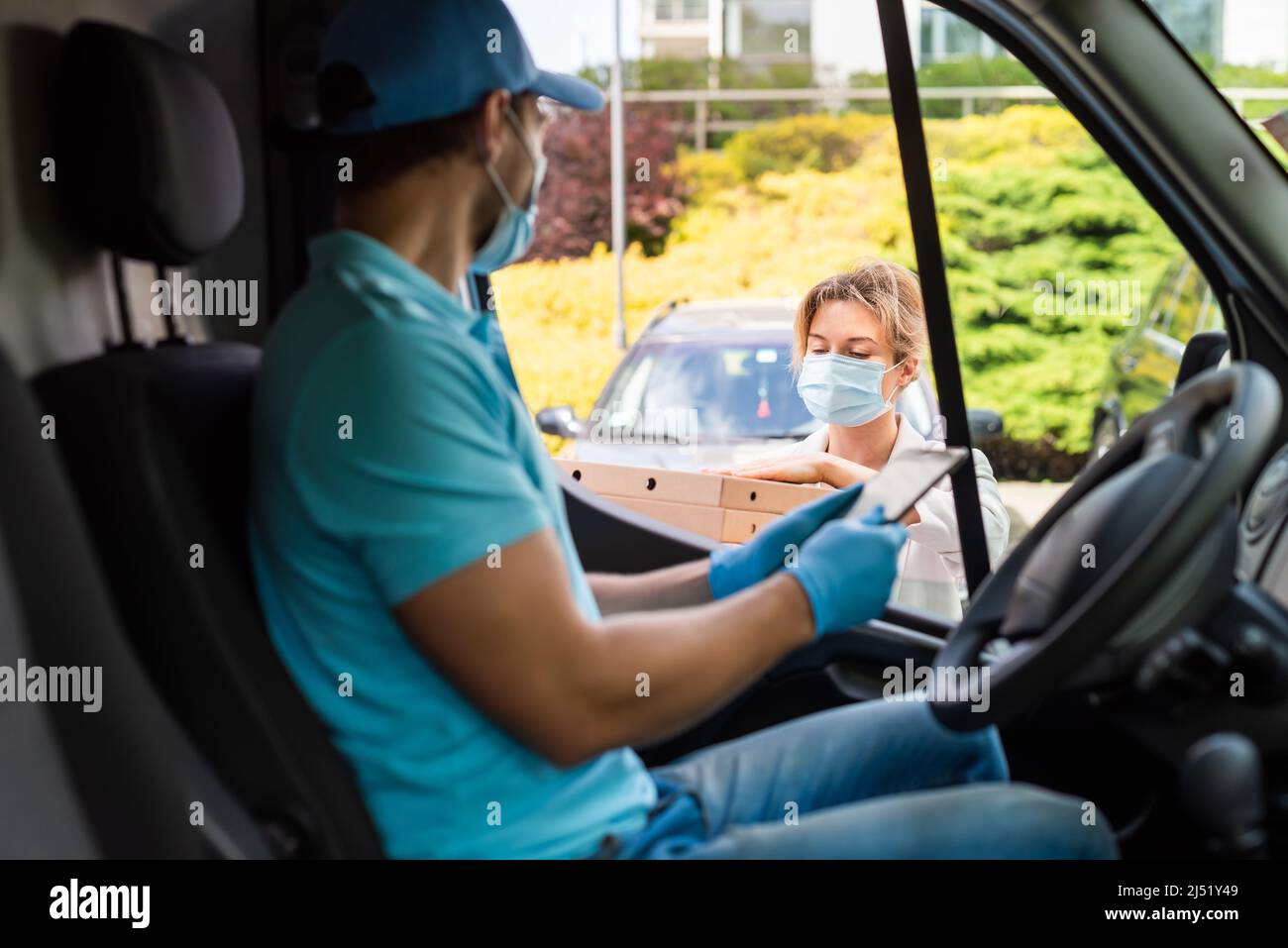 Safe delivery - Young male courier on a van brings a pizza to the ...
