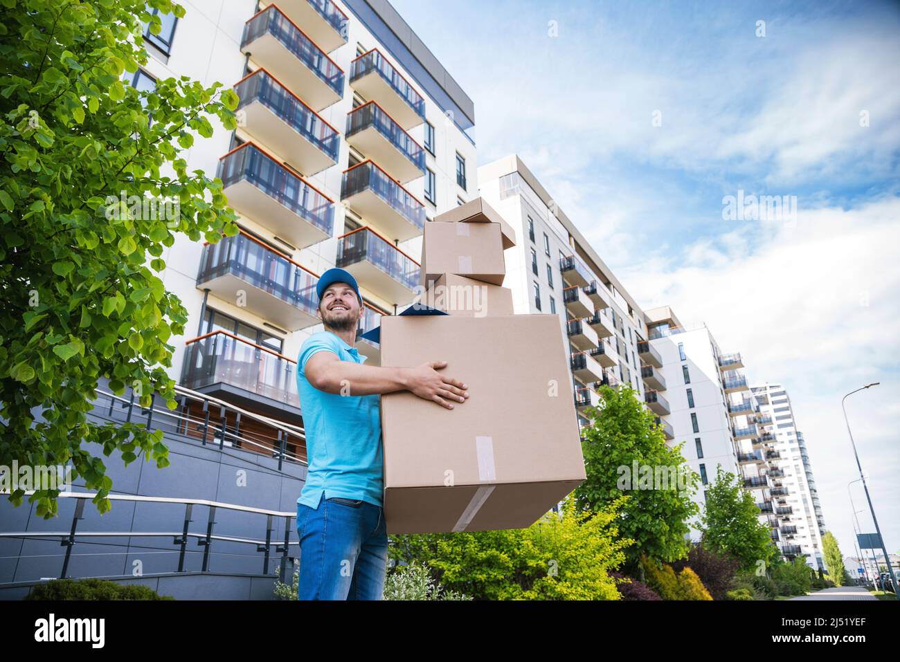 Strong delivery man holding a stack of a cardboard boxes on a city ...